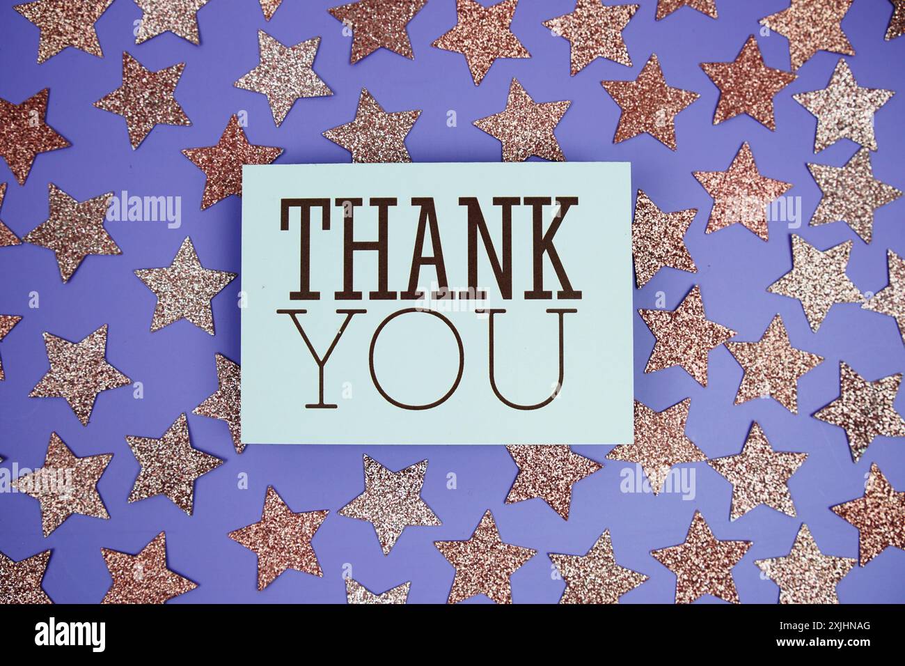 Thank You card flat lay on purple background with pink glitter star ...