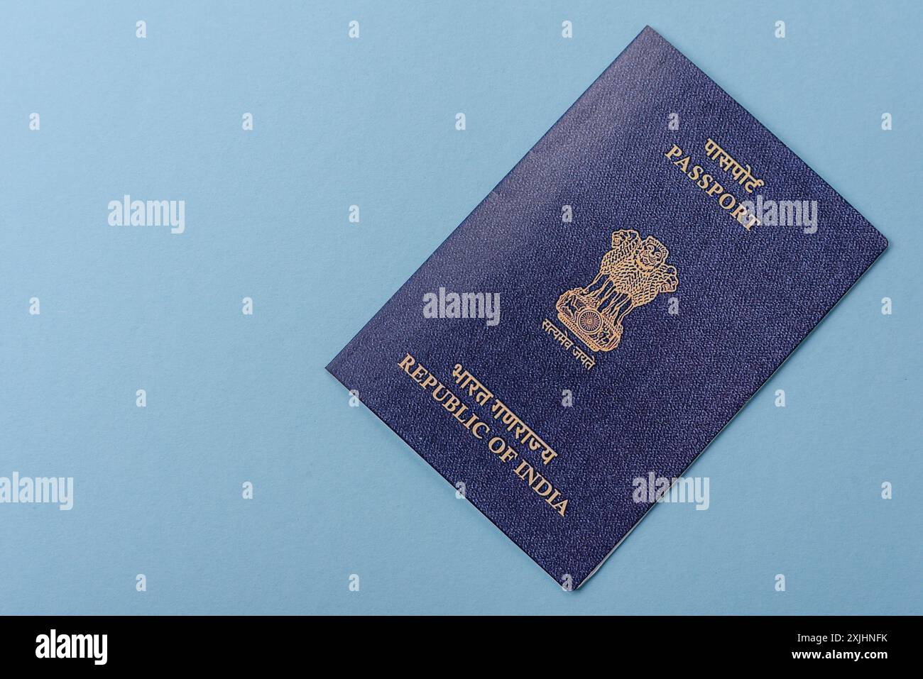 Physical paper international passport of Indian citizen on a blue ...
