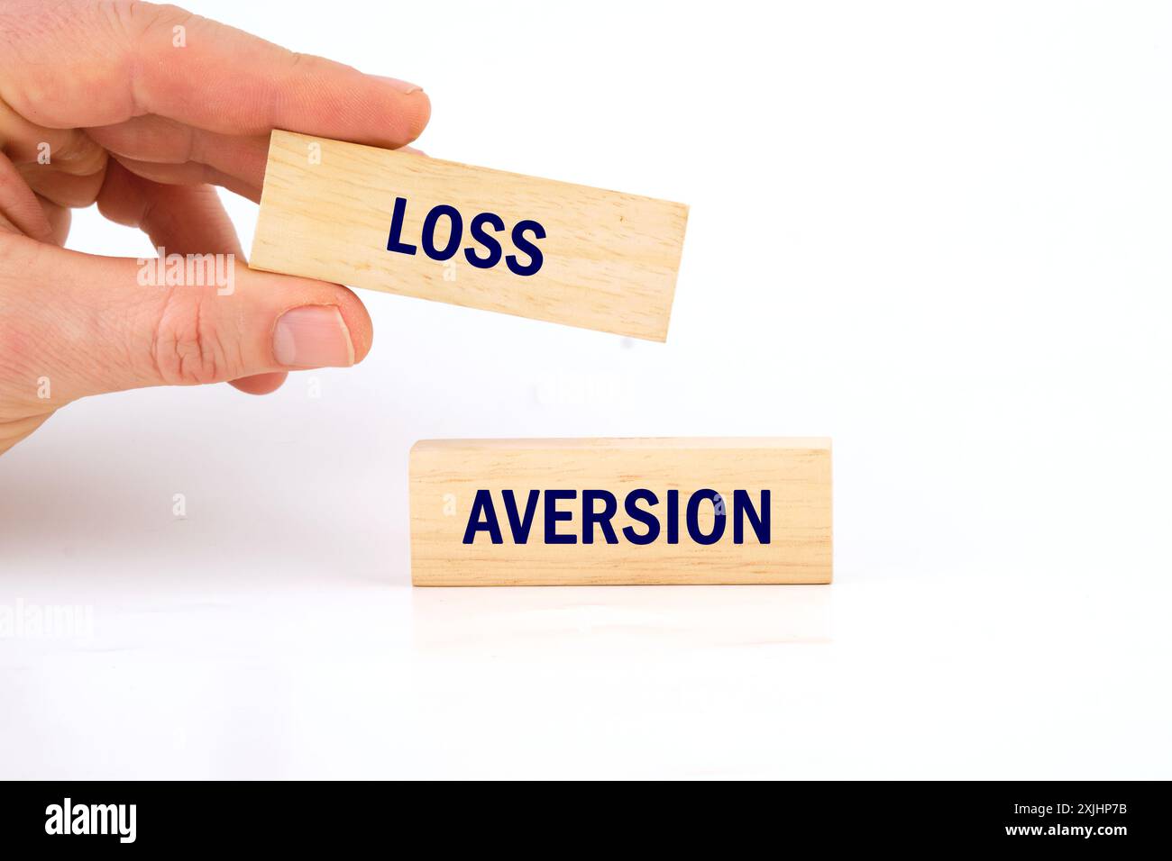 LOSS AVERSION text written on wooden blocks with a man's hand on a ...