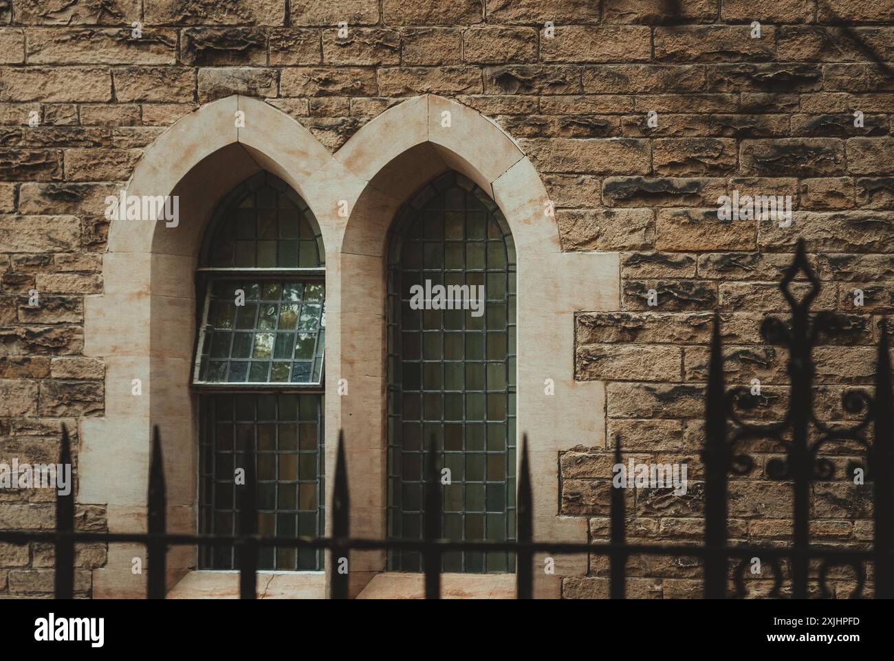 Two arched windows with intricate mullions are set into a weathered ...