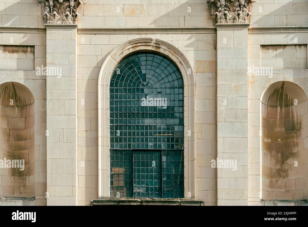 A large arched window with a grid of panes, framed by an ornate stone ...