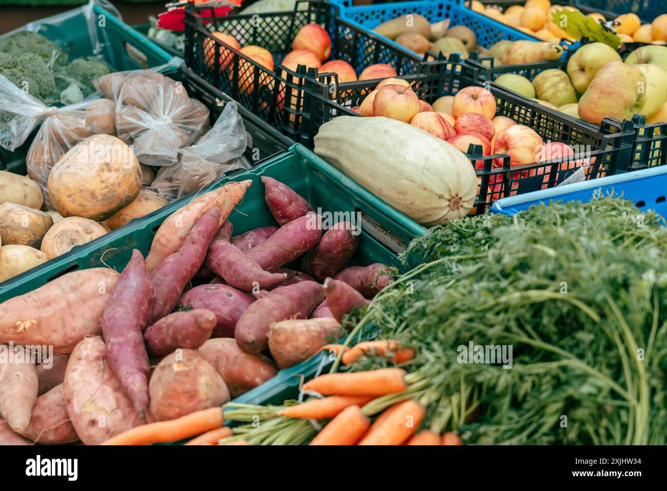 A variety of fresh produce sits in plastic crates at a market. Sweet ...