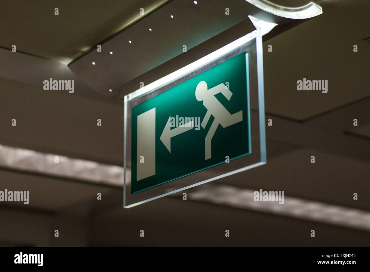 The image captures an illuminated exit sign mounted on the ceiling. The ...