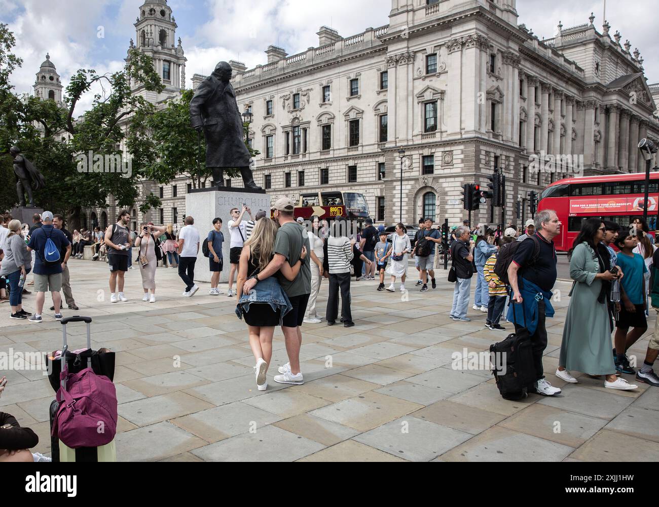 People take photographs in Parliament Square, London, as many tourists ...