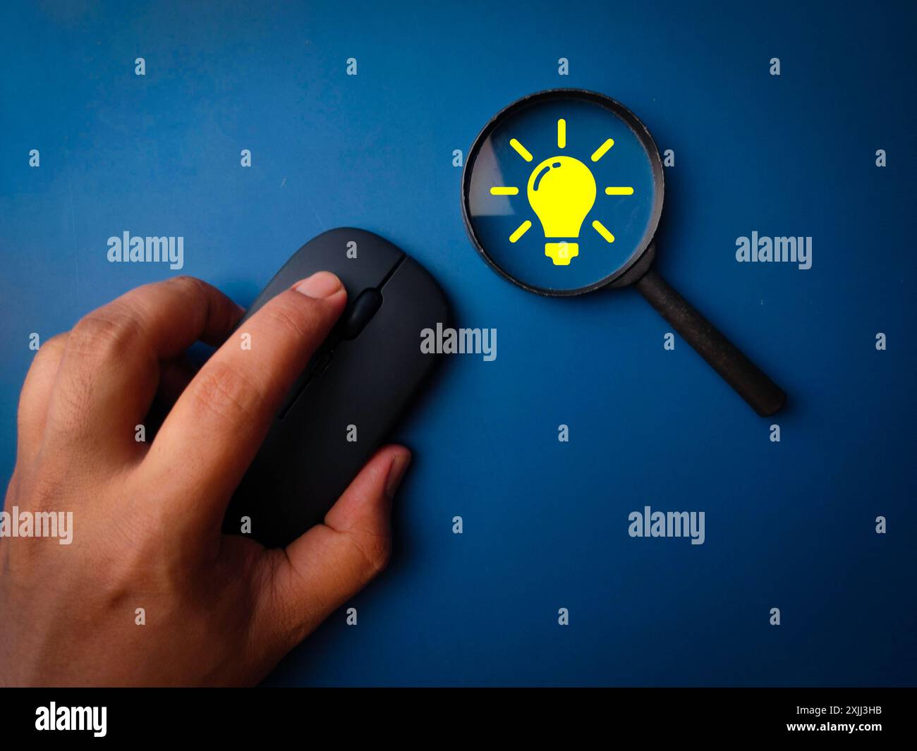 Hand holding black mouse and magnifying glass with light bulb icon on a ...