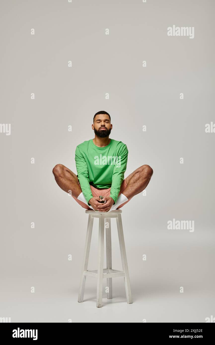 Handsome African American man sitting on a stool with his legs crossed ...
