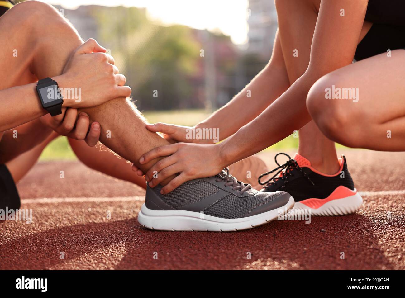 Sports injury. Woman helping man with leg pain at stadium, closeup ...