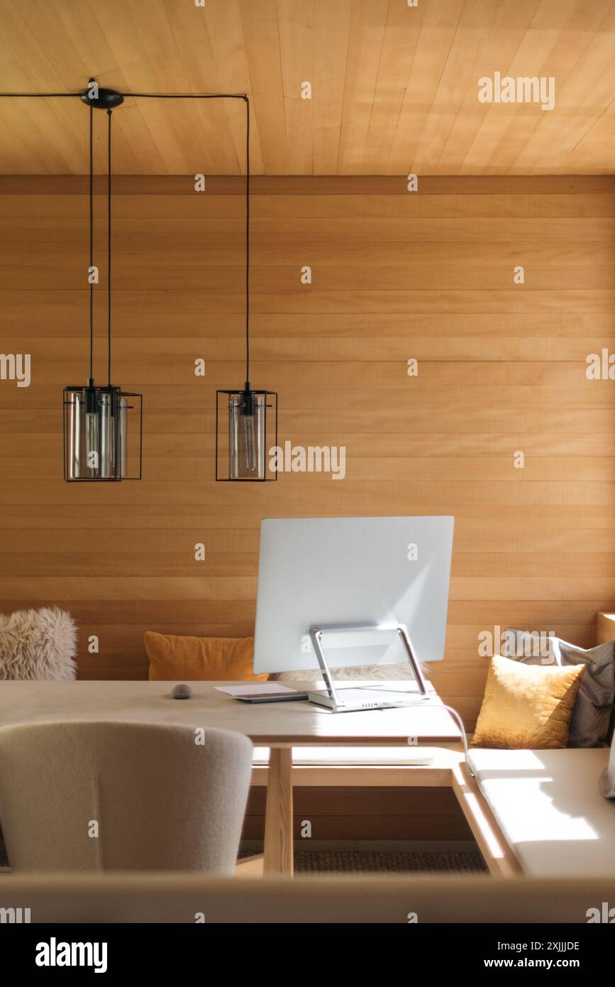 Modern workspace with computer, pendant lights, and cozy seating Stock ...