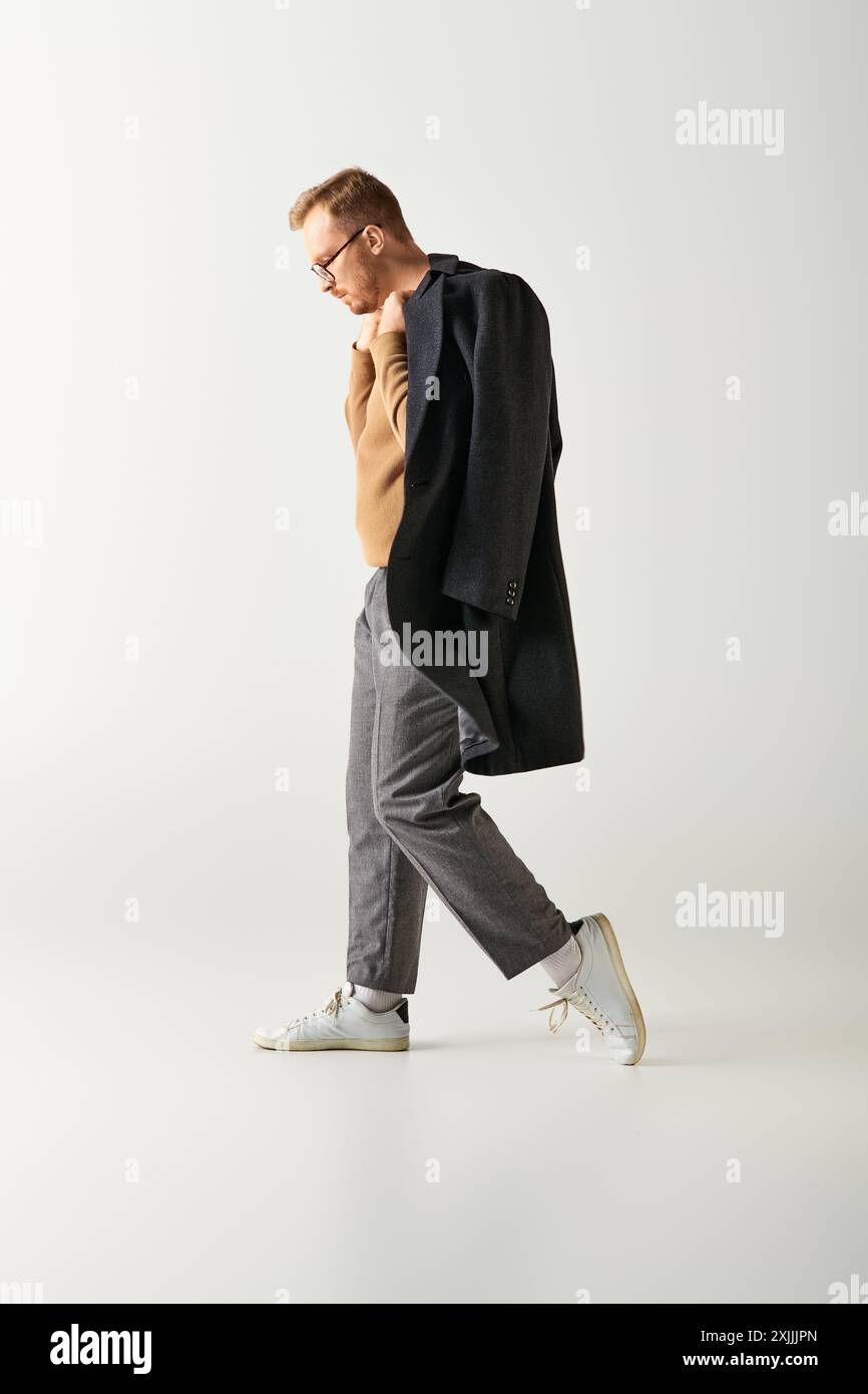 A stylish man in a black jacket is confidently walking Stock Photo - Alamy