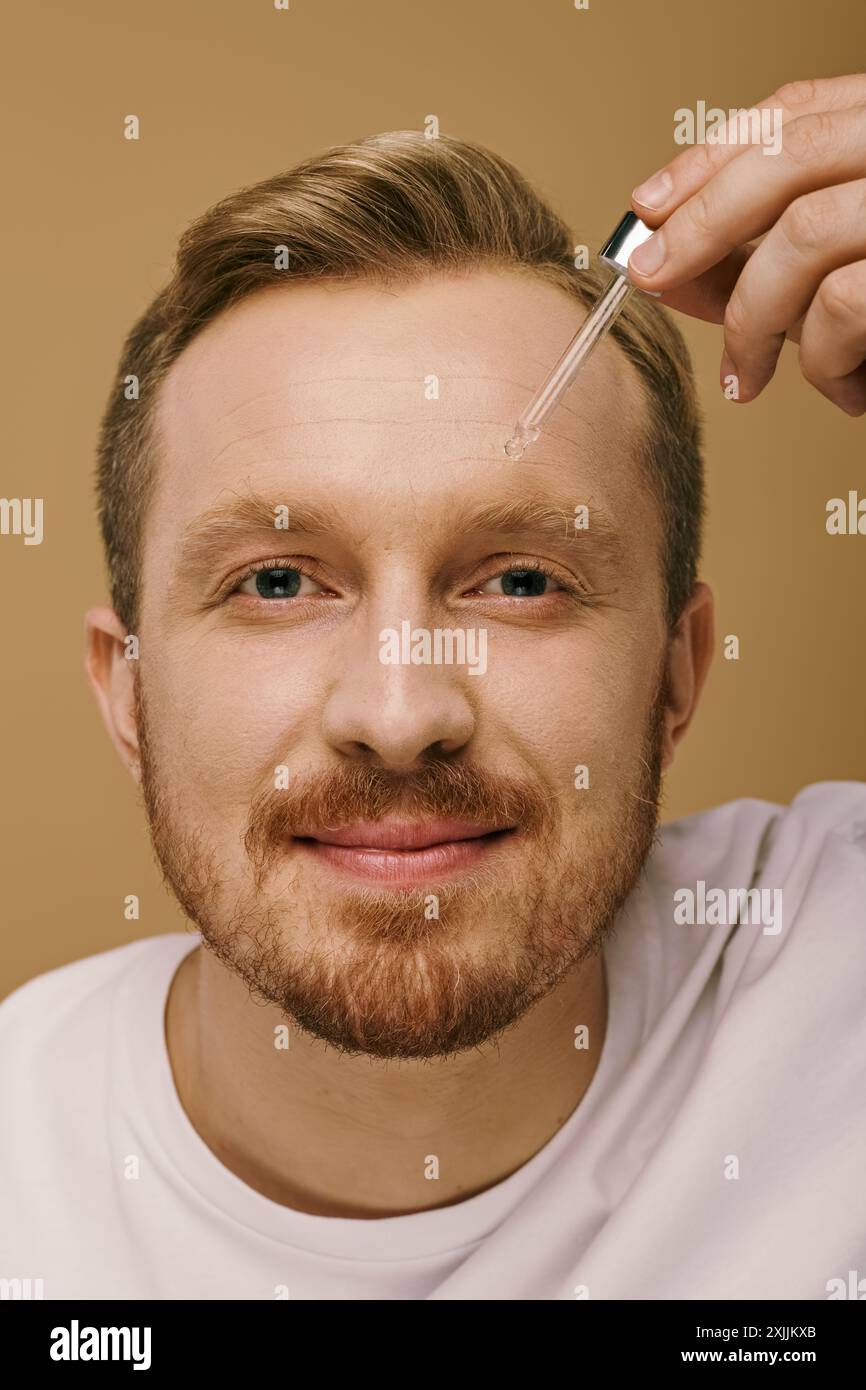 Man using serum on pastel backdrop Stock Photo - Alamy