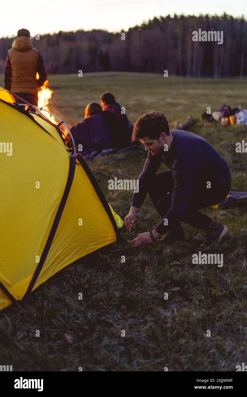 man sets up a tent on a camping trip, camping sunset tent Stock Photo ...