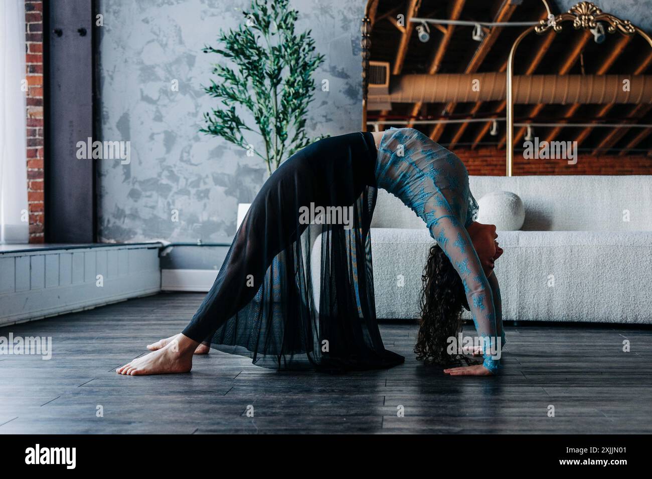 Woman in blue lace top performing a backbend in a stylish studio Stock ...