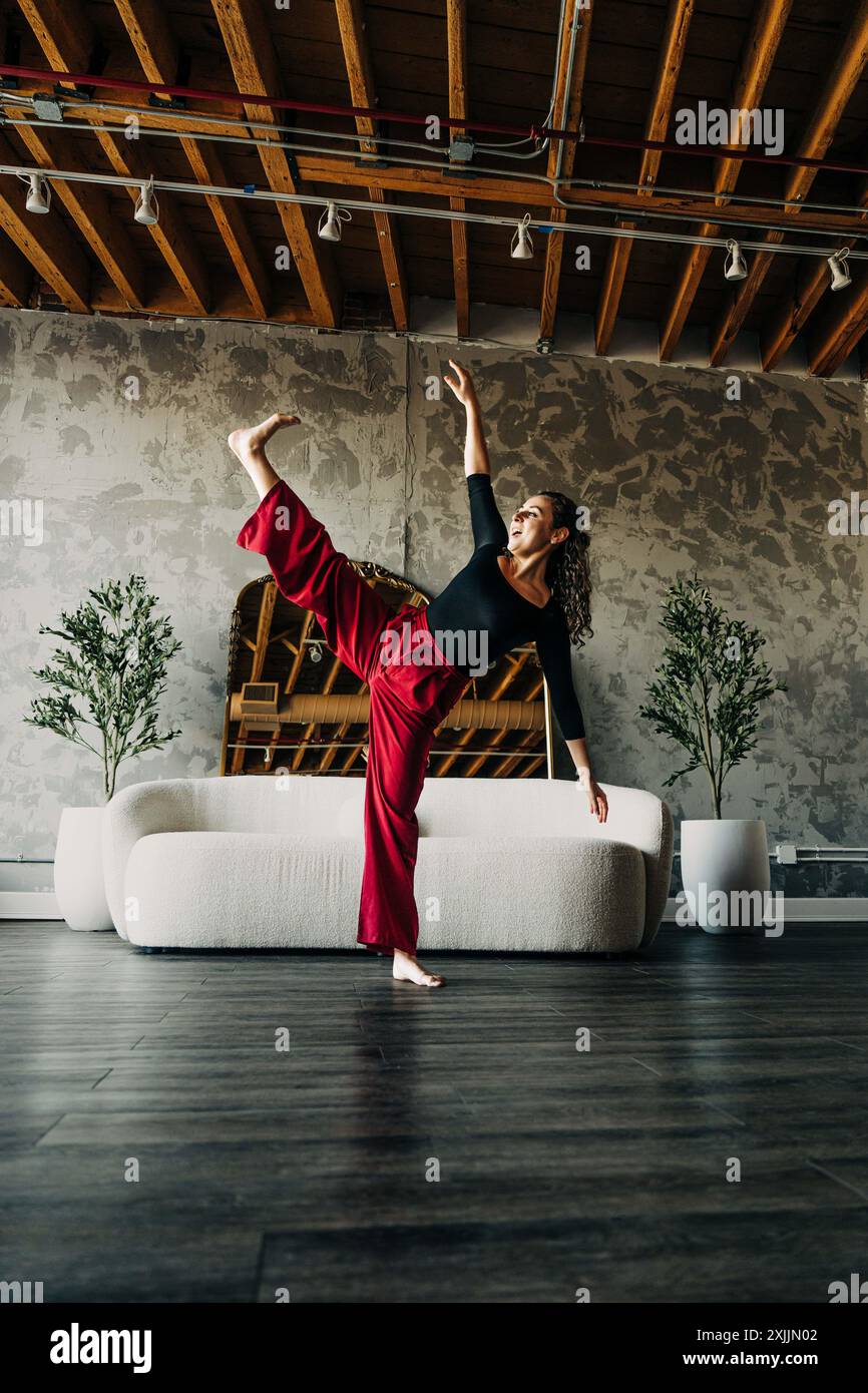 Woman joyfully performing a balanced yoga pose wearing red pants Stock ...