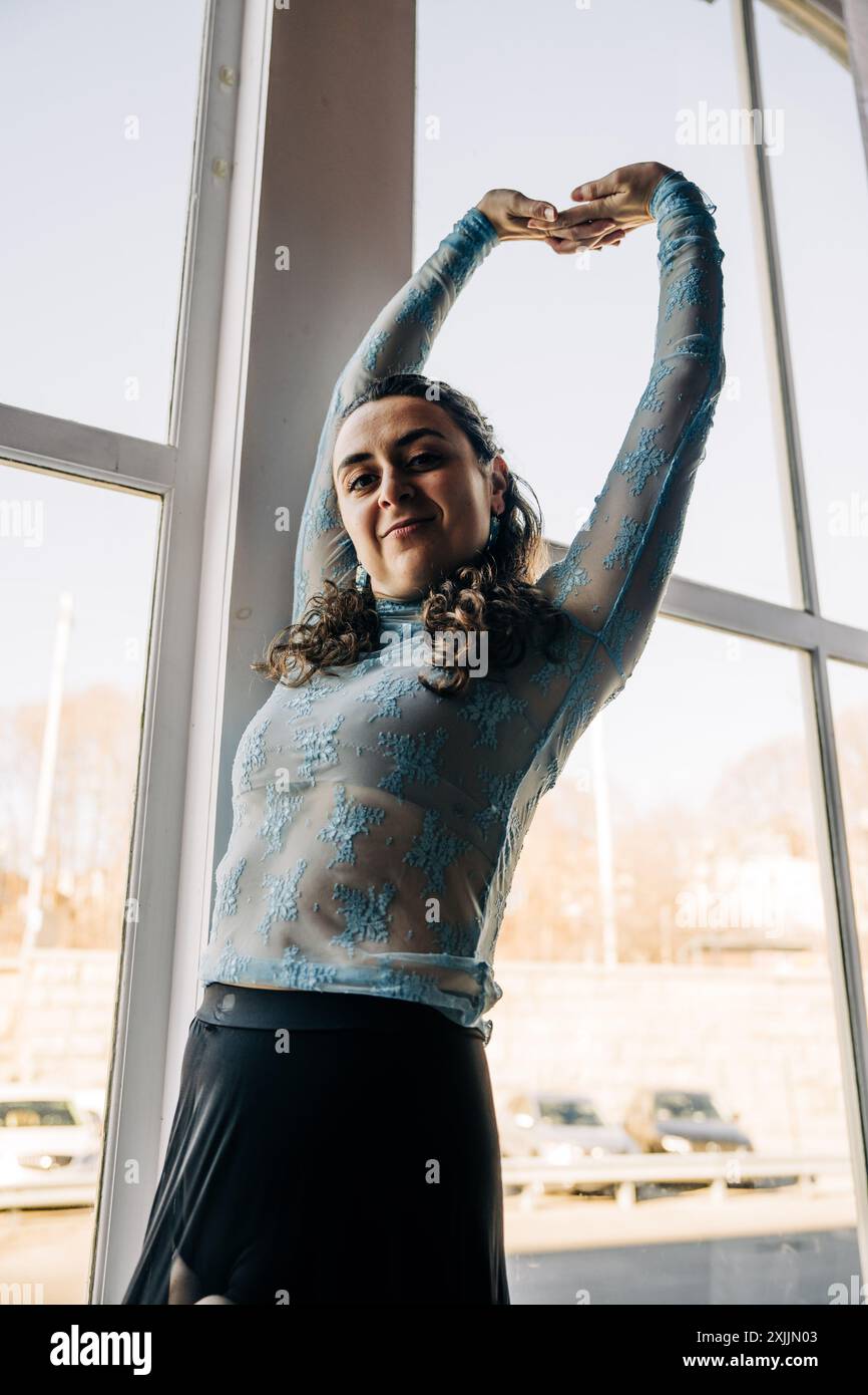 Confident Woman in blue lace top stretching by a window Stock Photo - Alamy