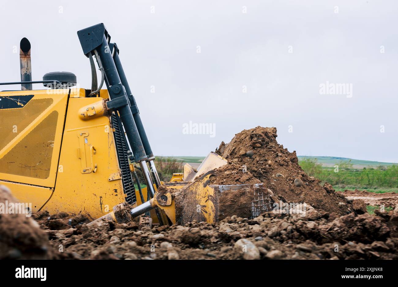 Close up of a bulldozer pushing dirt in field Stock Photo - Alamy