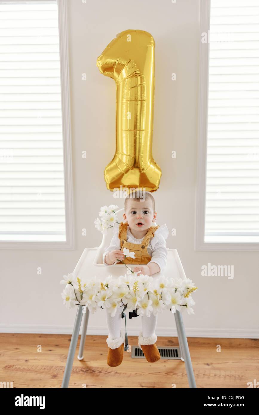 Adorable baby celebrating first birthday with balloon and floral decor ...