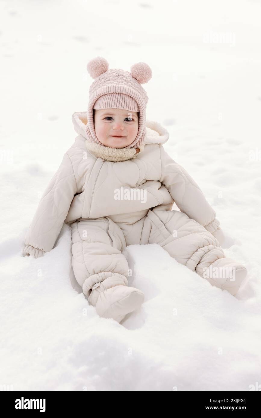 Adorable baby bundled up, sitting in snow, enjoying winter weather ...