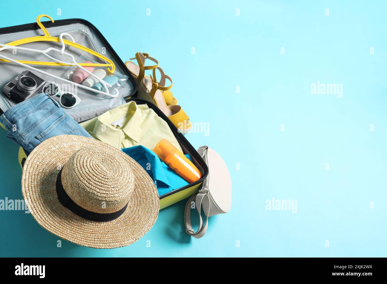 Open suitcase with traveler's belongings on light blue background ...