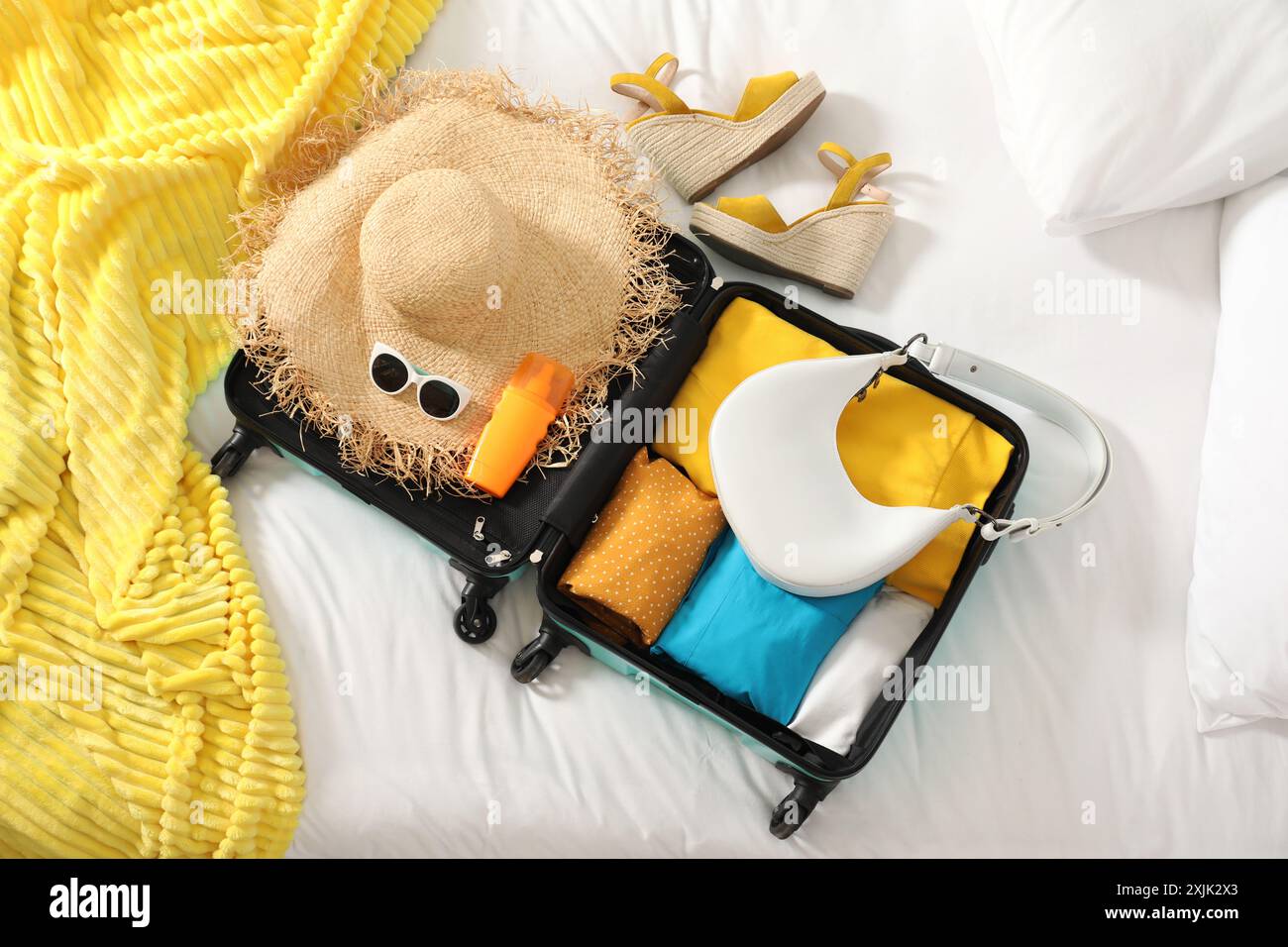 Open suitcase with traveler's belongings on bed, flat lay Stock Photo ...