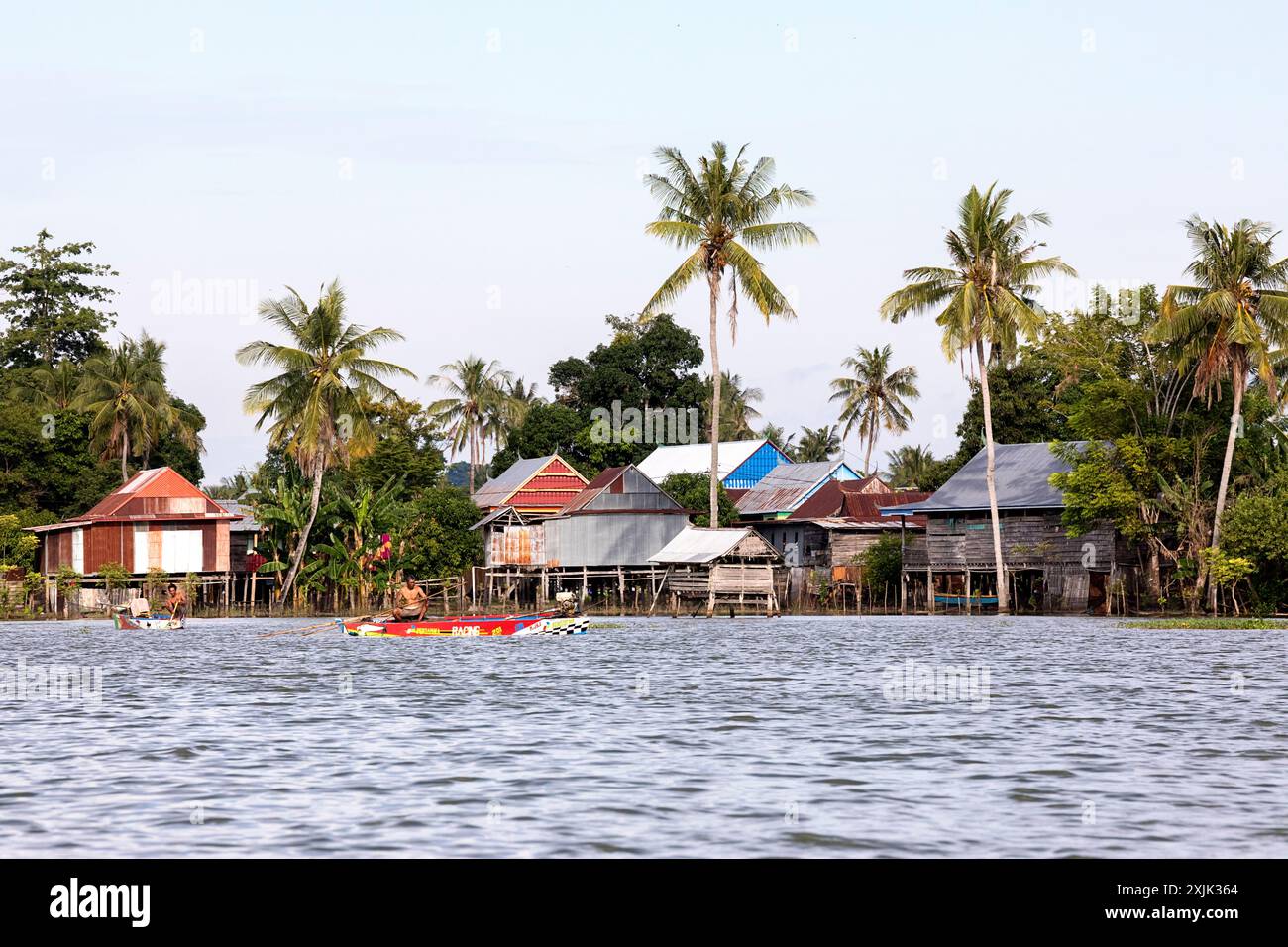 floating houses in a village surrounded with palm trees in the middle ...