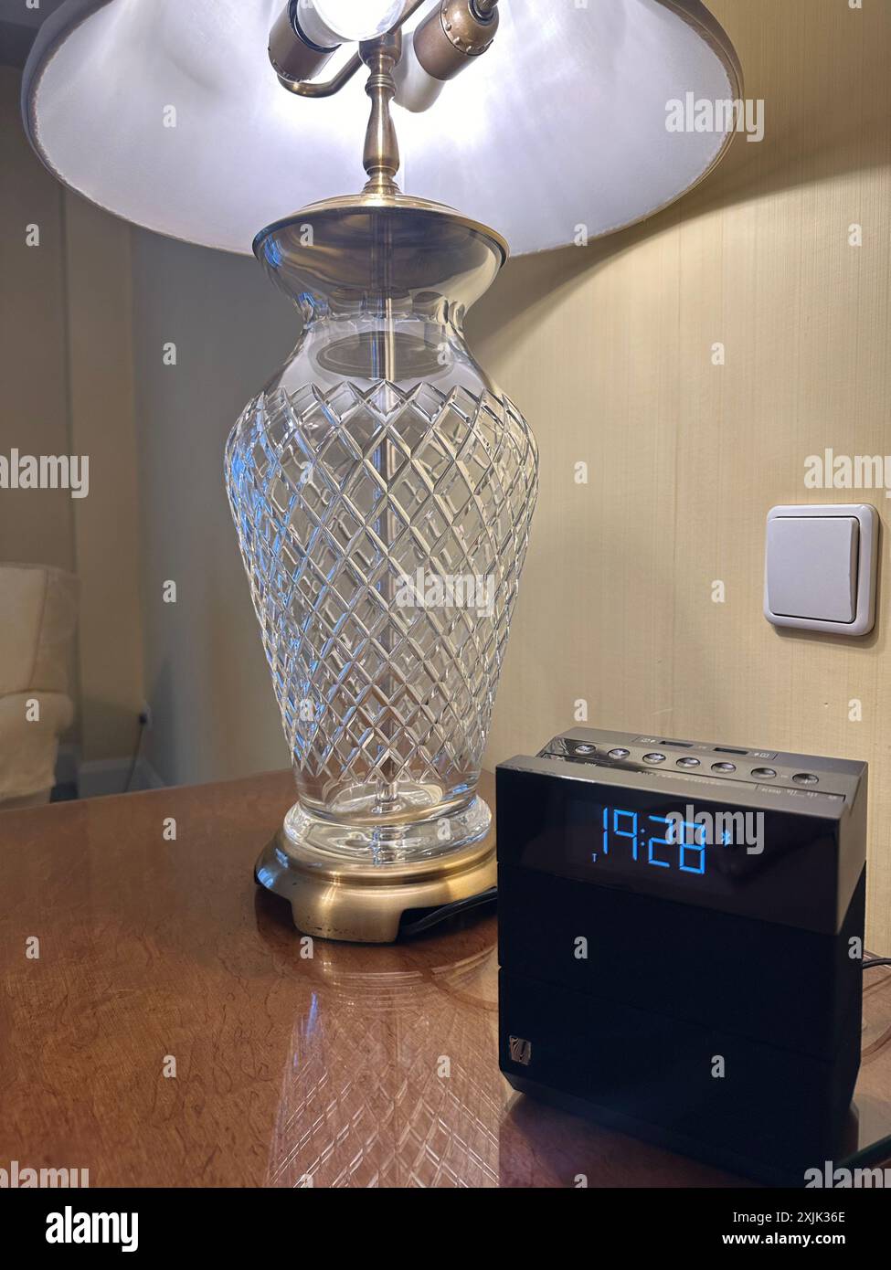 Lamp and electric clock on wooden bedside in luxury hotel Stock Photo ...