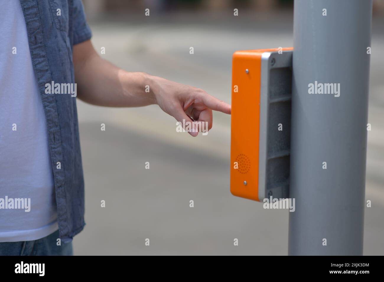 Close-up of a man pushing a crosswalk signal button on a traffic light ...