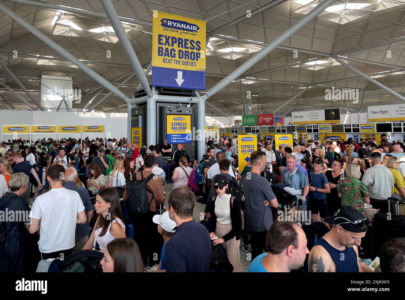 Passengers queue by the Ryanair check-in desk at London Stansted ...