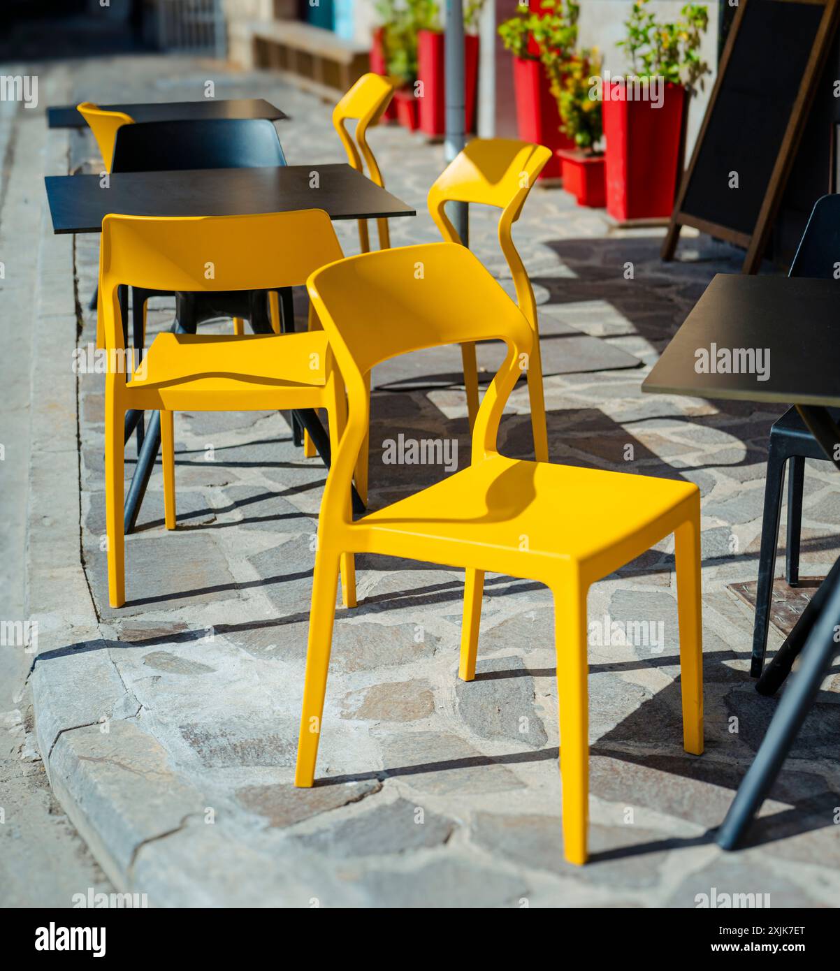 Bright, modern yellow and black chairs set up in an outdoor cafe. The ...