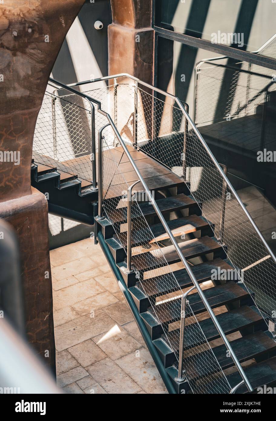 A contemporary industrial staircase with metal railings and mesh ...