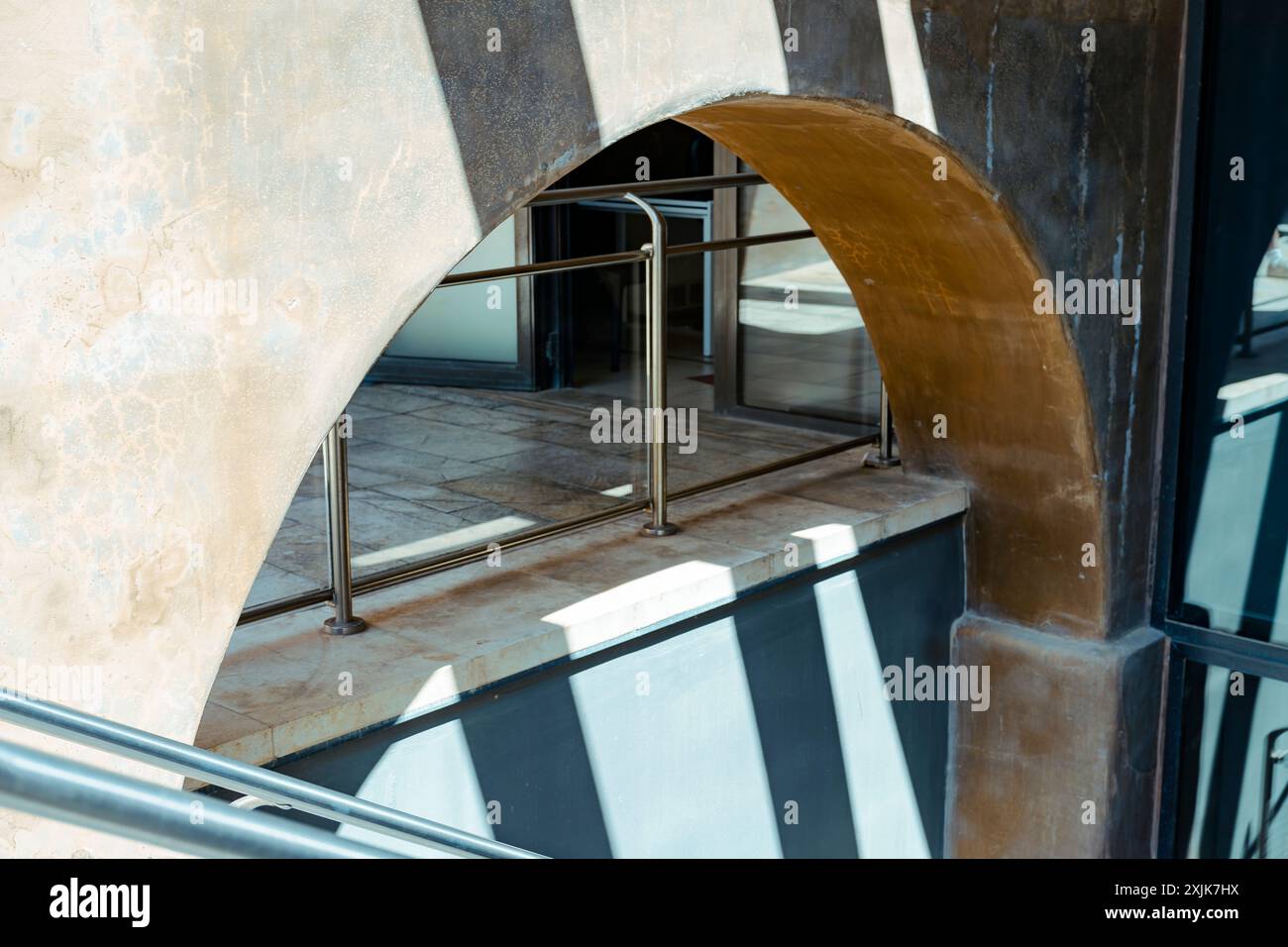 Interior view of a modern building featuring a large archway, sunlight ...