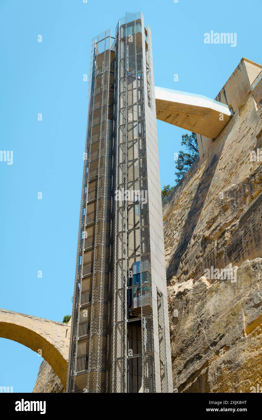 A tall modern elevator structure built next to a rugged rocky cliff ...
