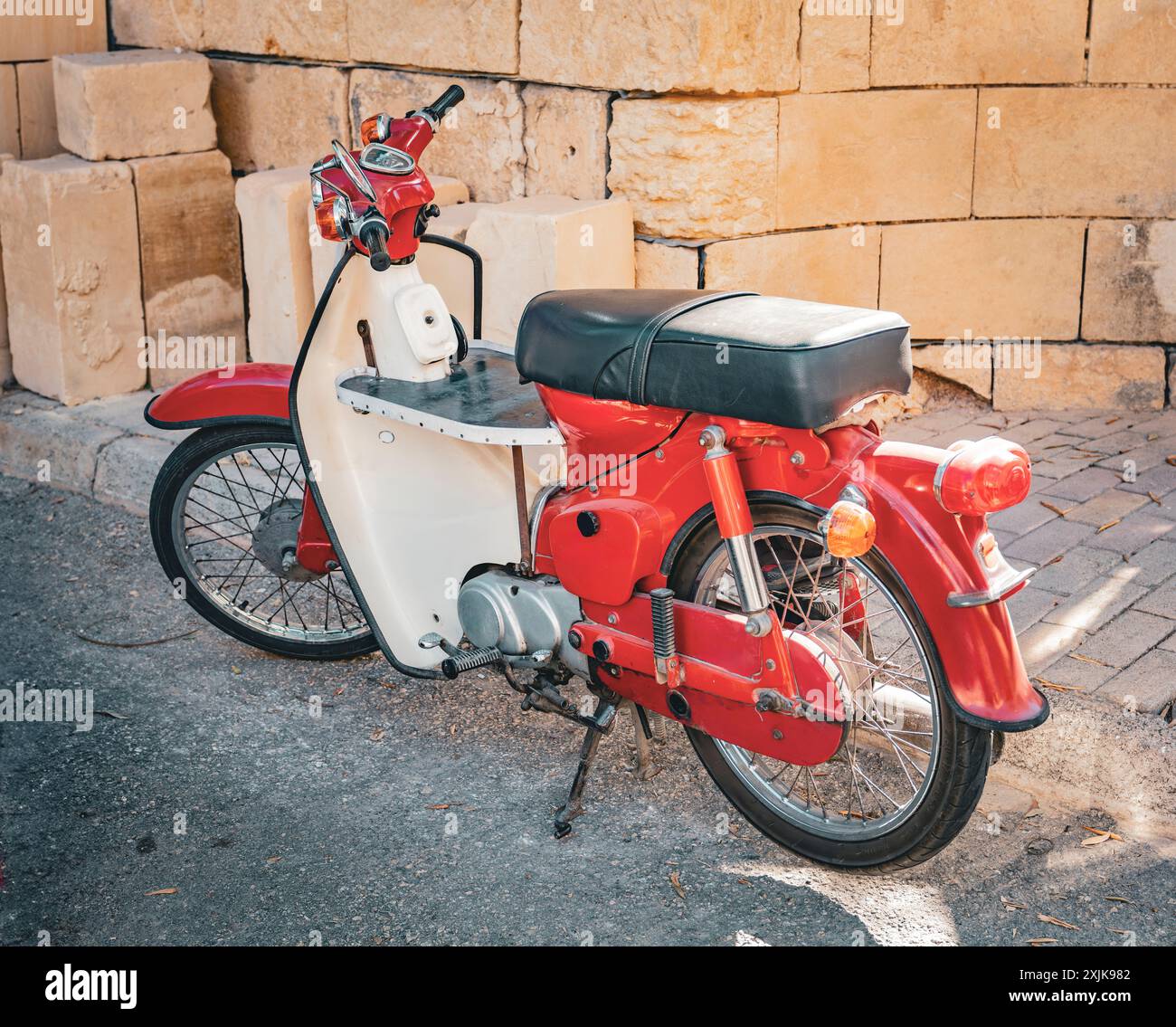 Retro red motorcycle parked on a street with old stone pavement and ...