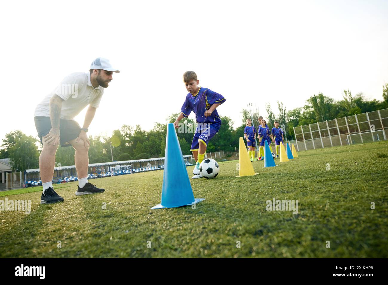 Young boy, child in motion, dribbling soccer ball around cones and ...
