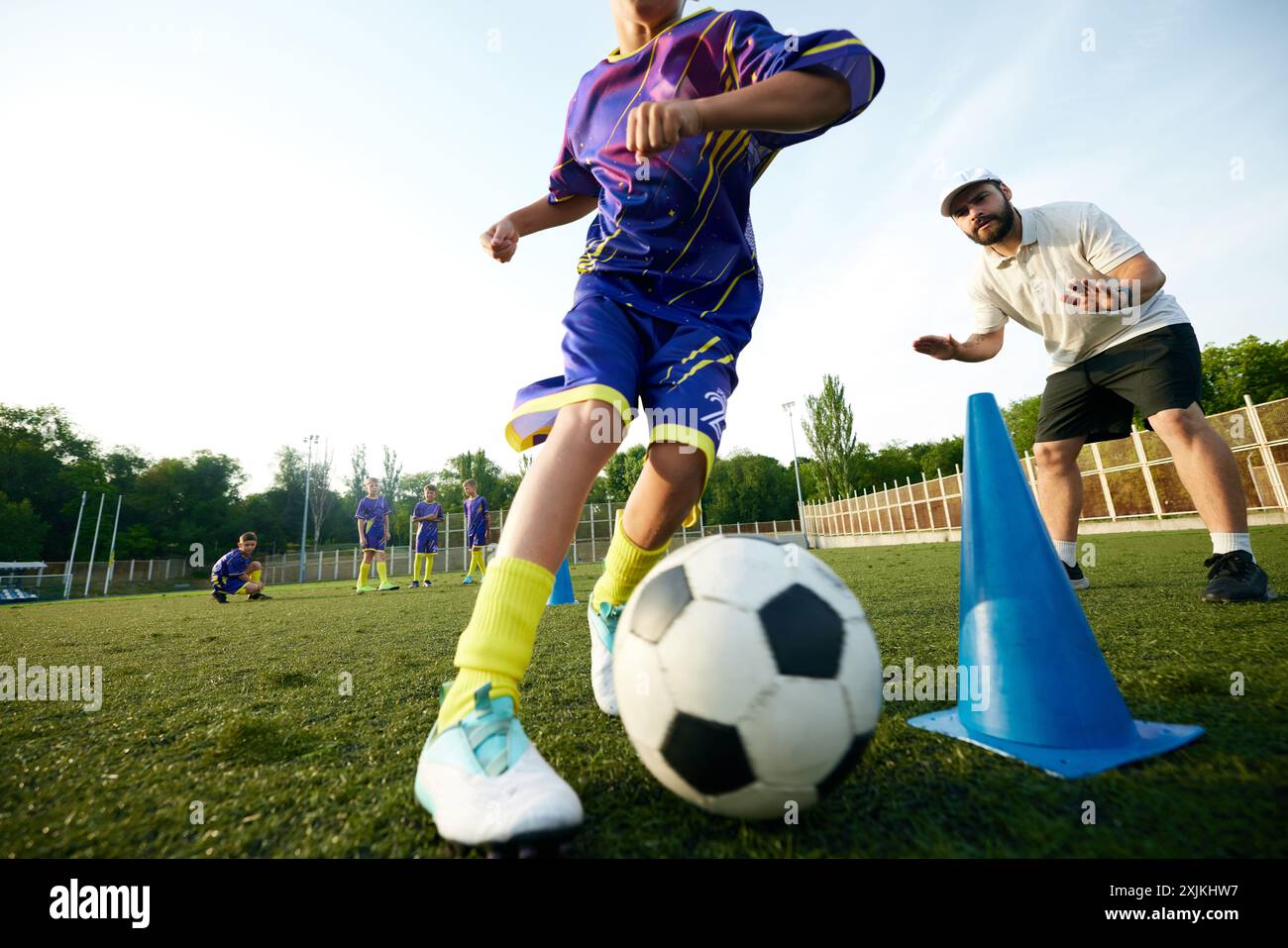 Focus on boys legs, child in motion, dribbling soccer ball around cones ...