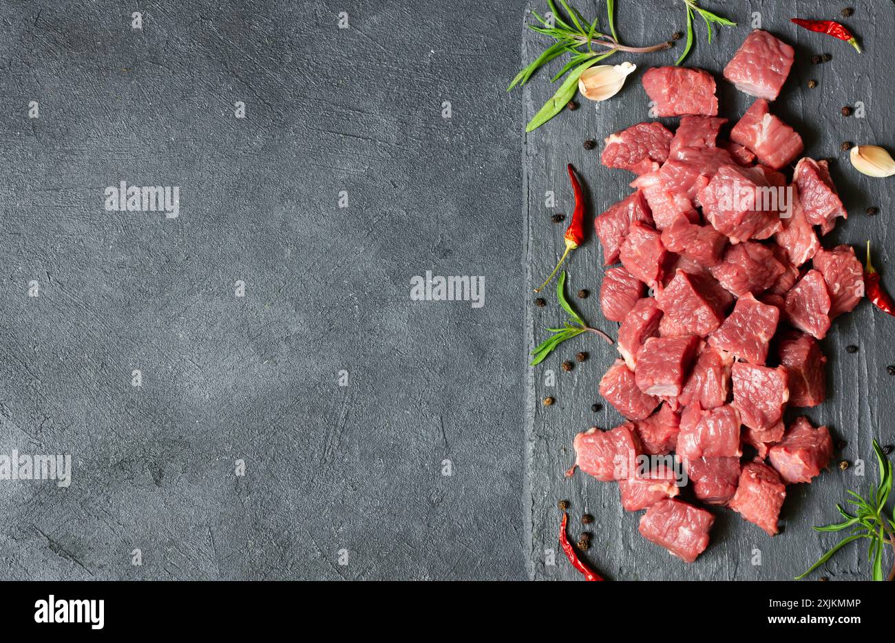 Diced cubed beef meat on stone board with thyme and peppers Stock Photo ...