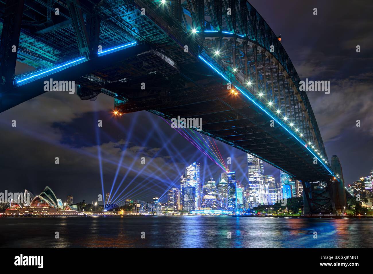A view of the skyline of Sydney, Australia, and the Harbour Bridge, both colorfully lit up ...