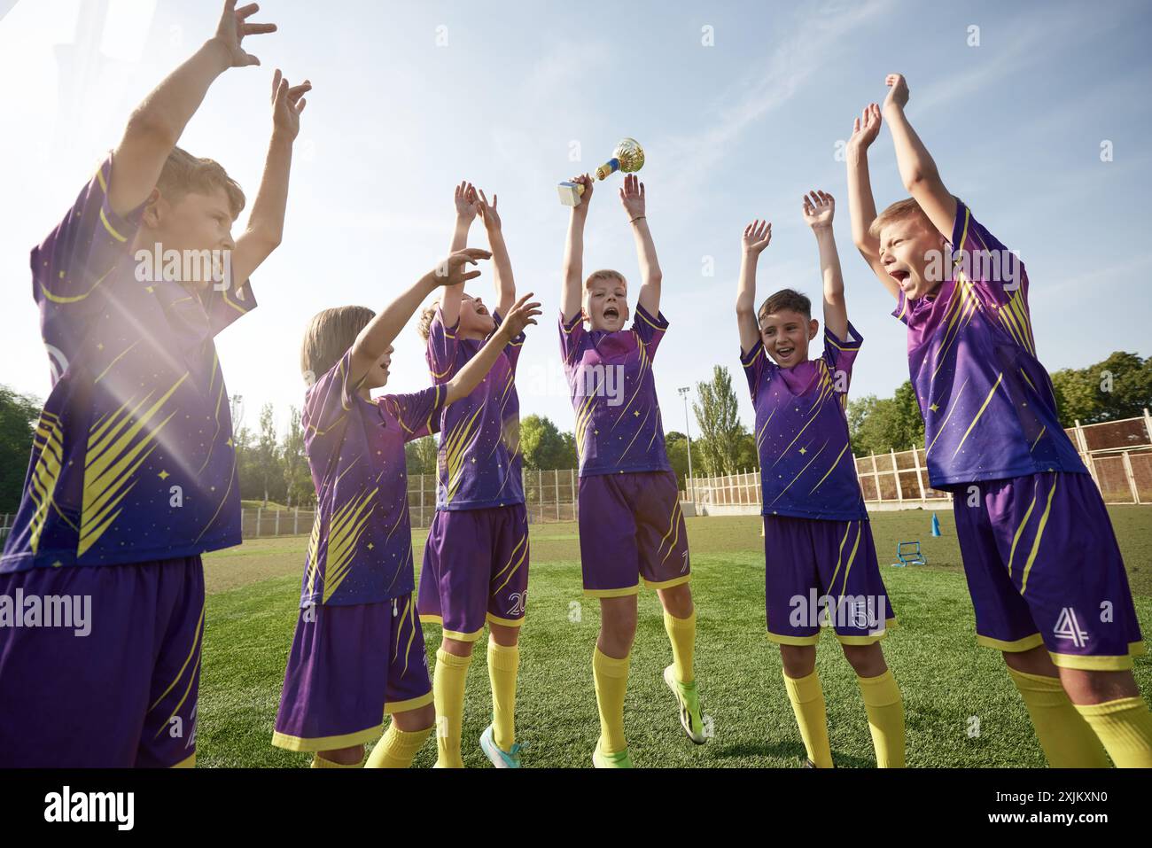 Happy children in purple sportswear raising trophy after winning game ...