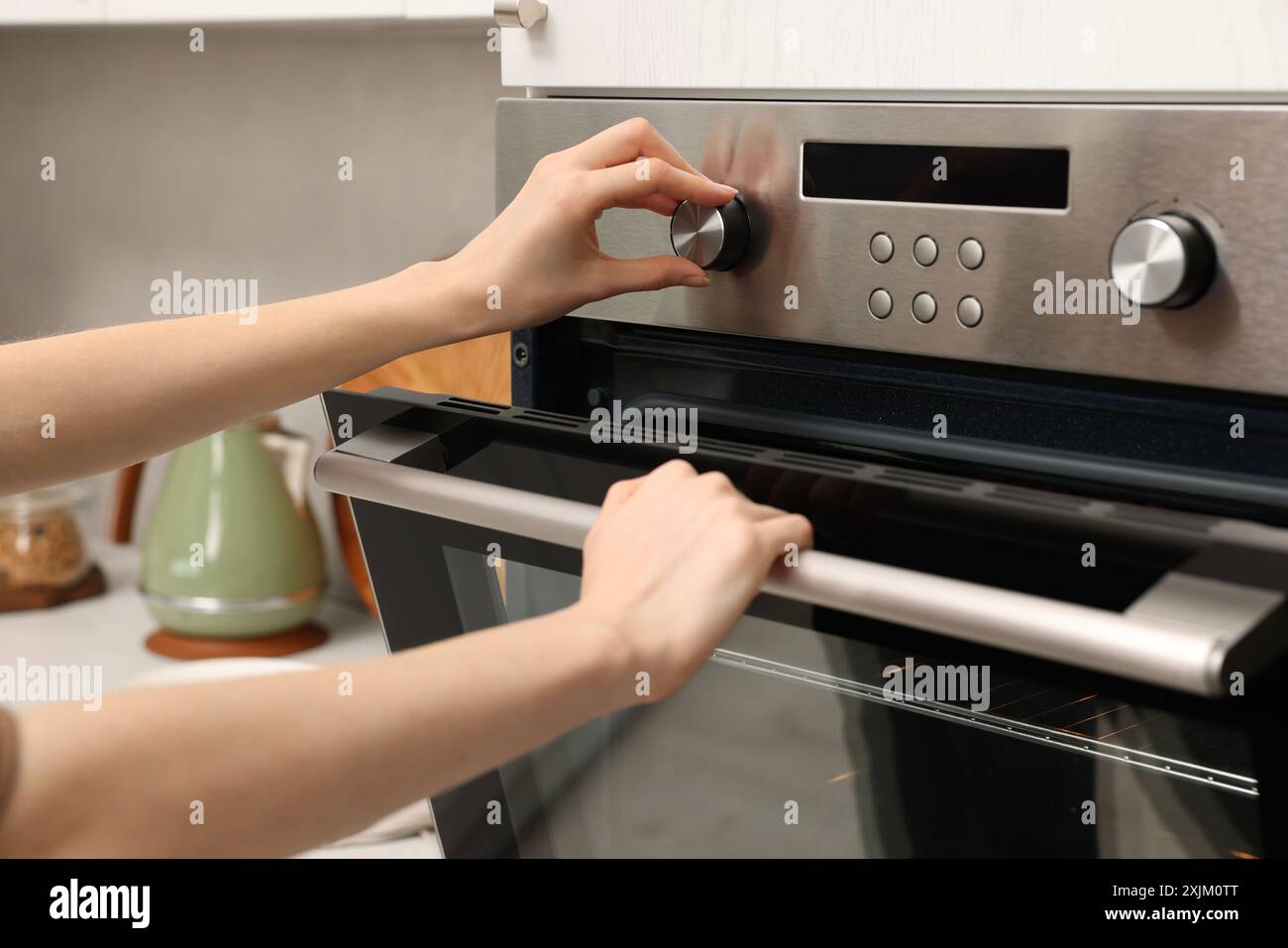 Woman using electric oven in kitchen, closeup Stock Photo - Alamy