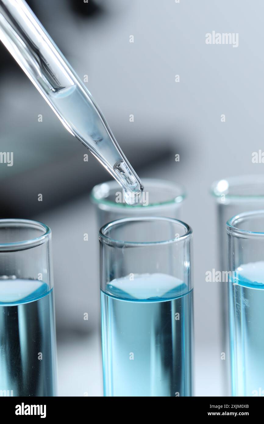 Dripping liquid from pipette into test tube on blurred background ...