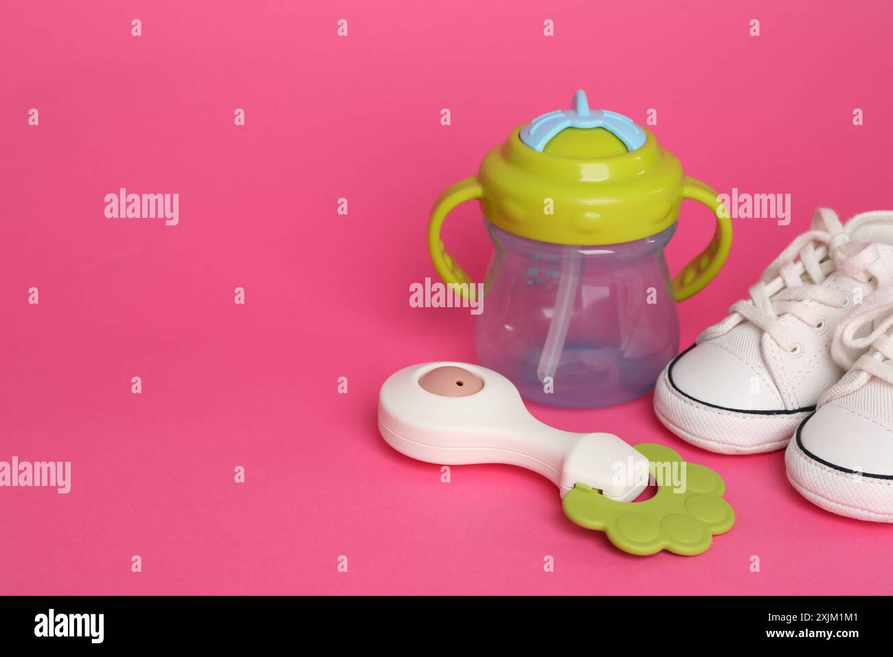 Baby rattle, bottle and booties on crimson background. Space for text ...