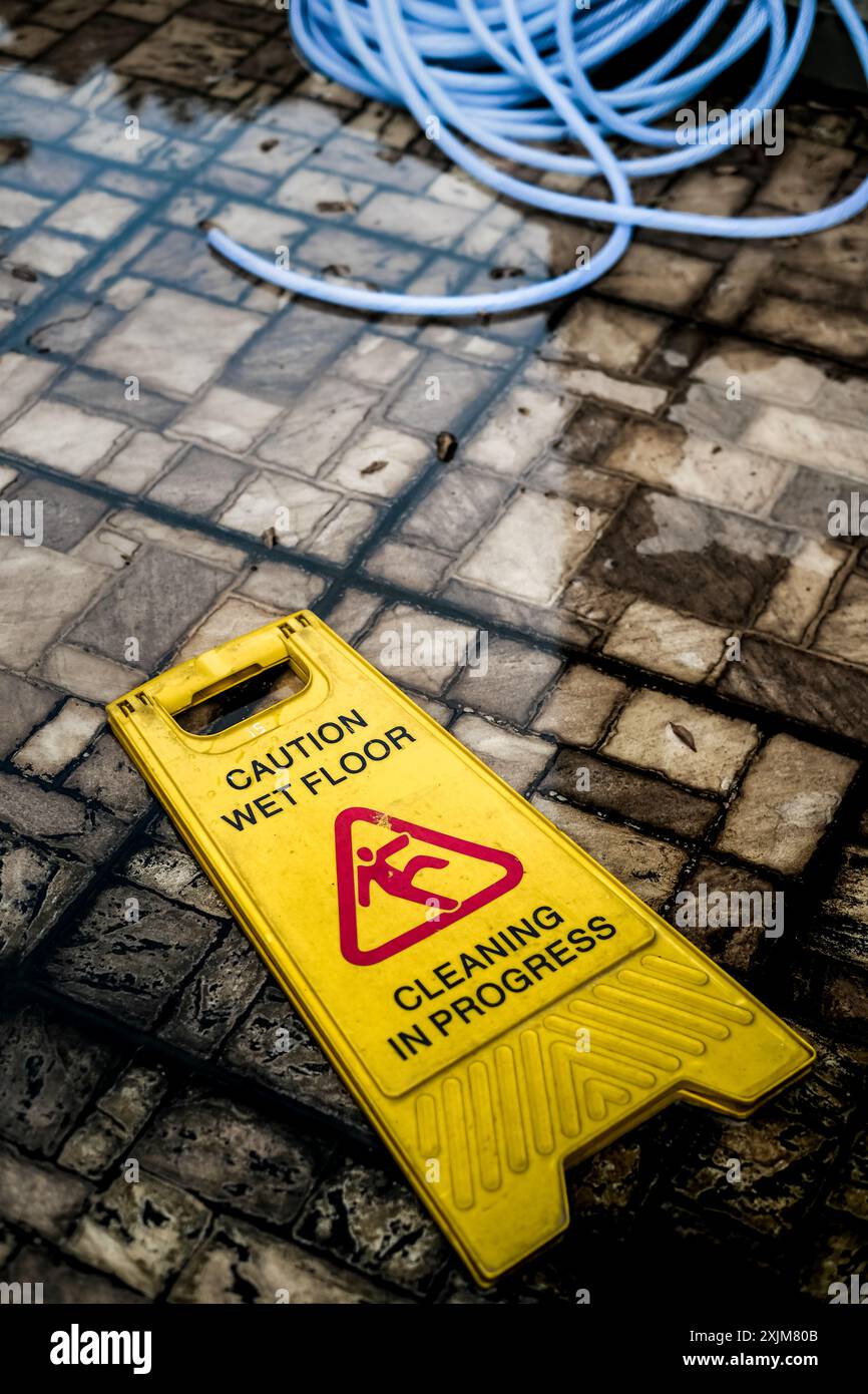Yellow Caution Wet Floor Cleaning in Progress Sign and Gardening Hose ...