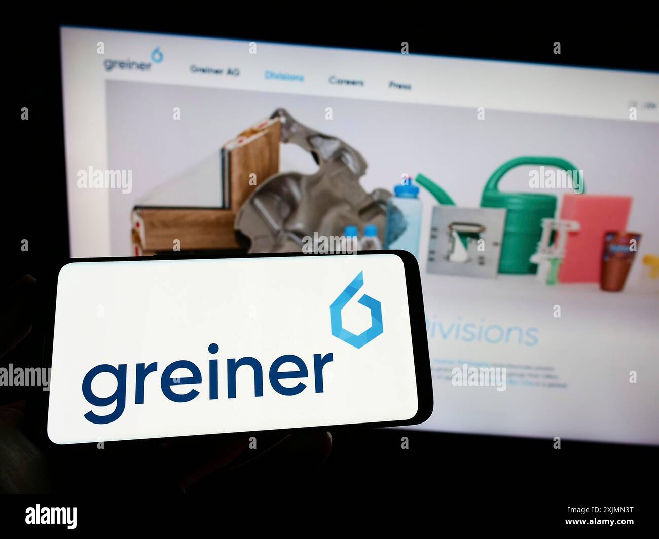 mobile phone with logo of Austrian plastics company Greiner AG on screen in front of business ...