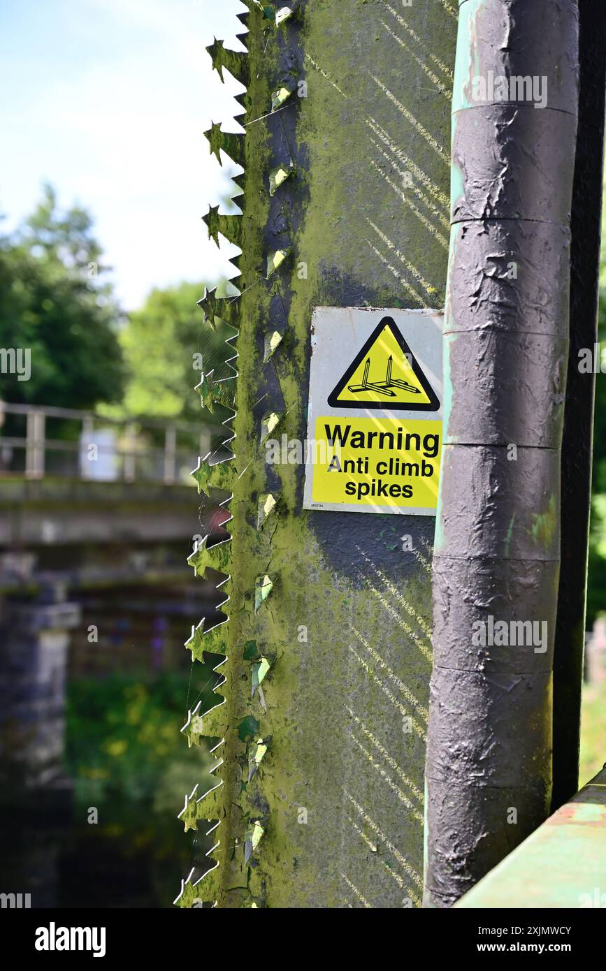 Anti-climb spikes and warning sign on the footbridge over the river ...
