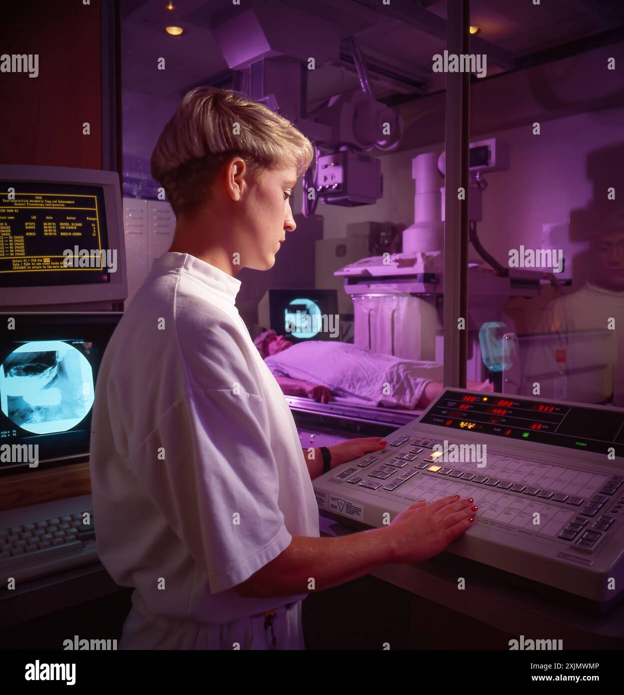 Female technician operates radiotherapy control panel while monitoring ...