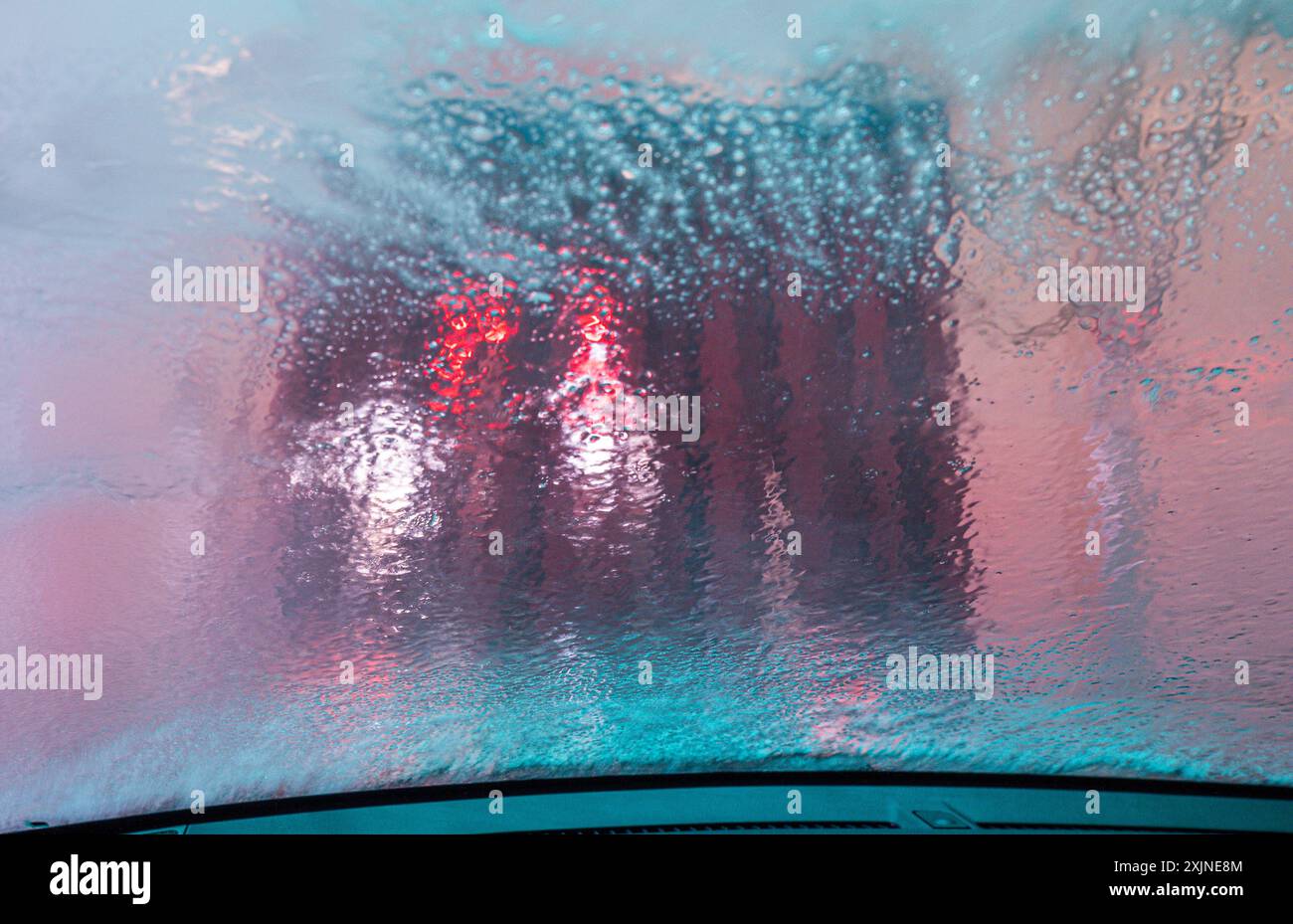 Soapy water sprays across automobile windshield as car moves through ...