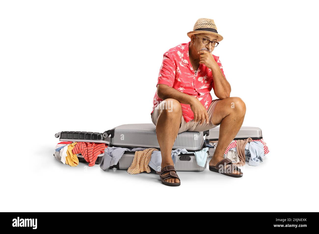 Sad mature male tourist sitting on a packed suitcase with messy clothes ...