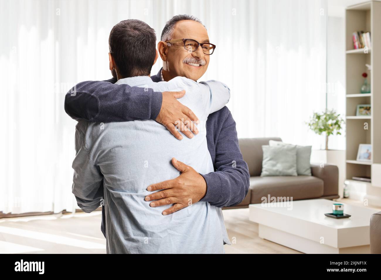 Happy men greeting each other with a hug at home in a living room Stock ...