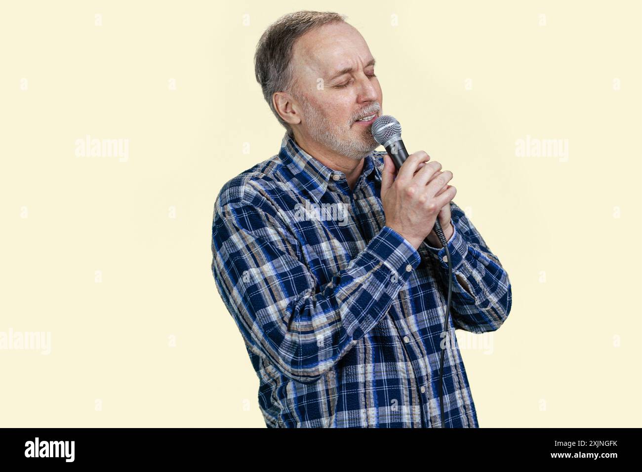 Portrait of a handsome mature man is singing a song in microphone ...