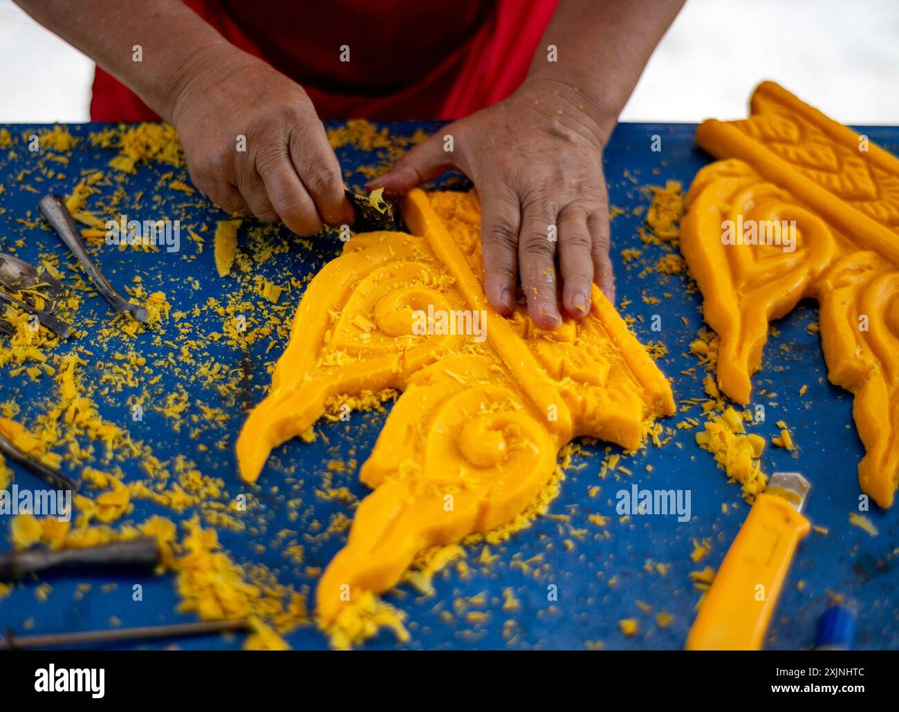 A Thai villager carves beeswax to decorate the candles for the Candle ...