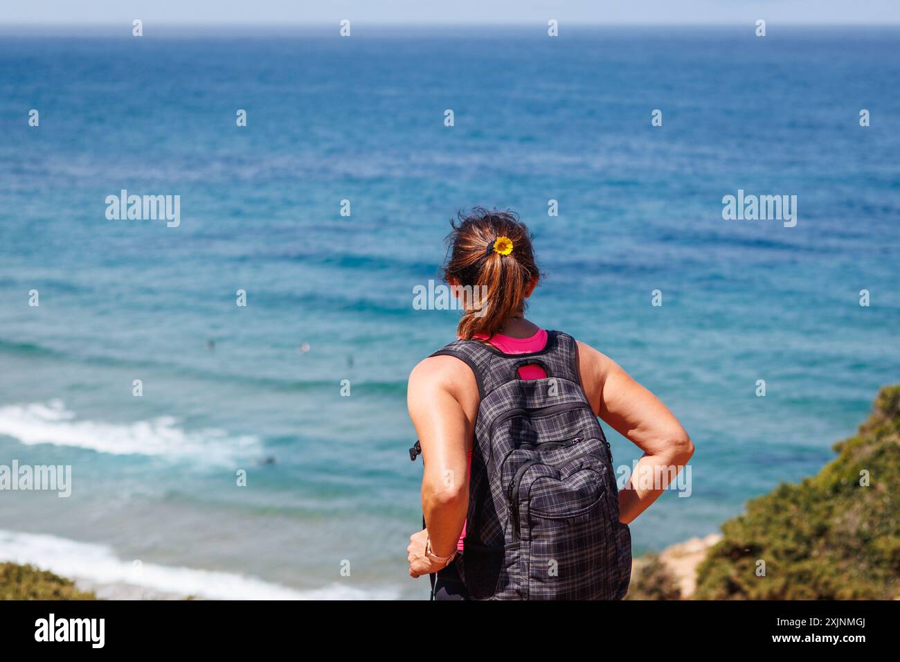 Sporty mature woman enjoying view from cliff to sea during hike on ...